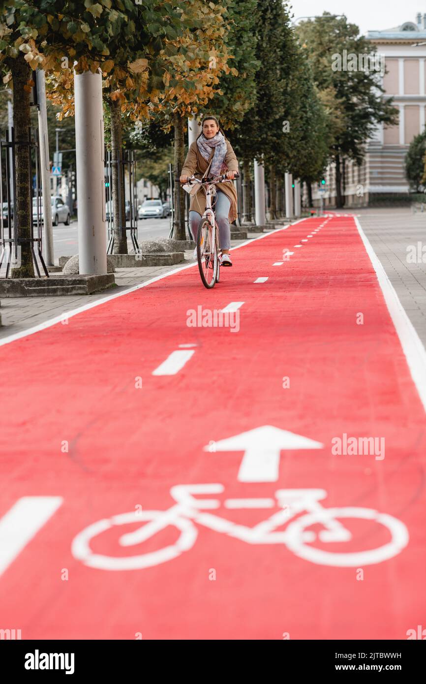 woman cycling along red bike lane road in city Stock Photo - Alamy