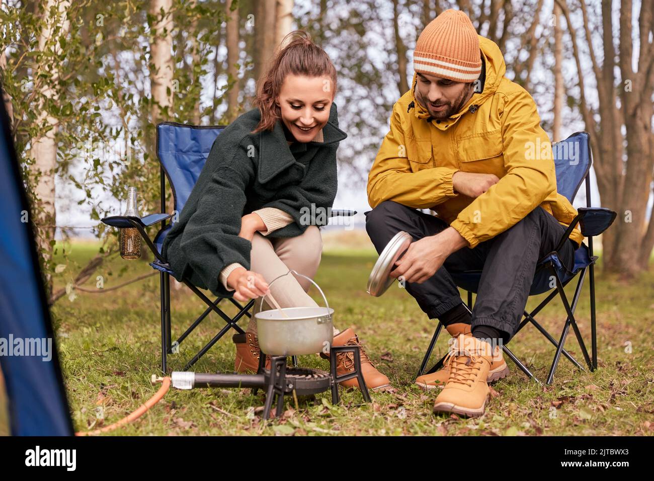 couple cooking food on gas burner at tent camp Stock Photo - Alamy