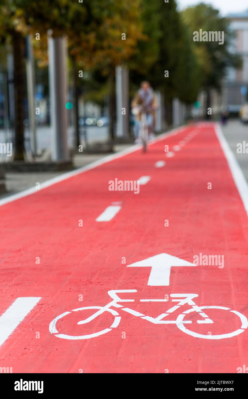 woman cycling along red bike lane road in city Stock Photo - Alamy