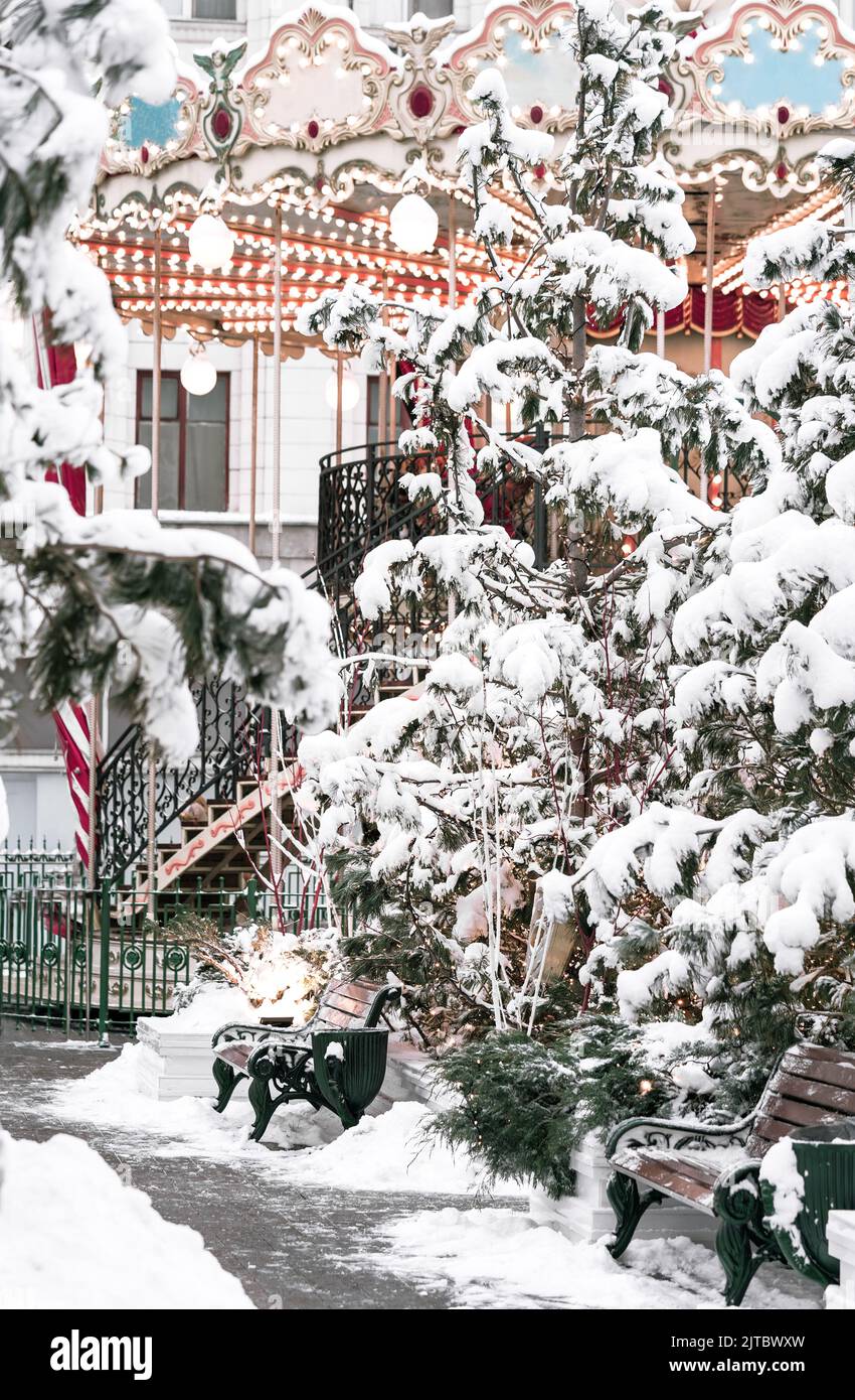Beautiful festive background with merry-go-round and snowy fir trees in ...