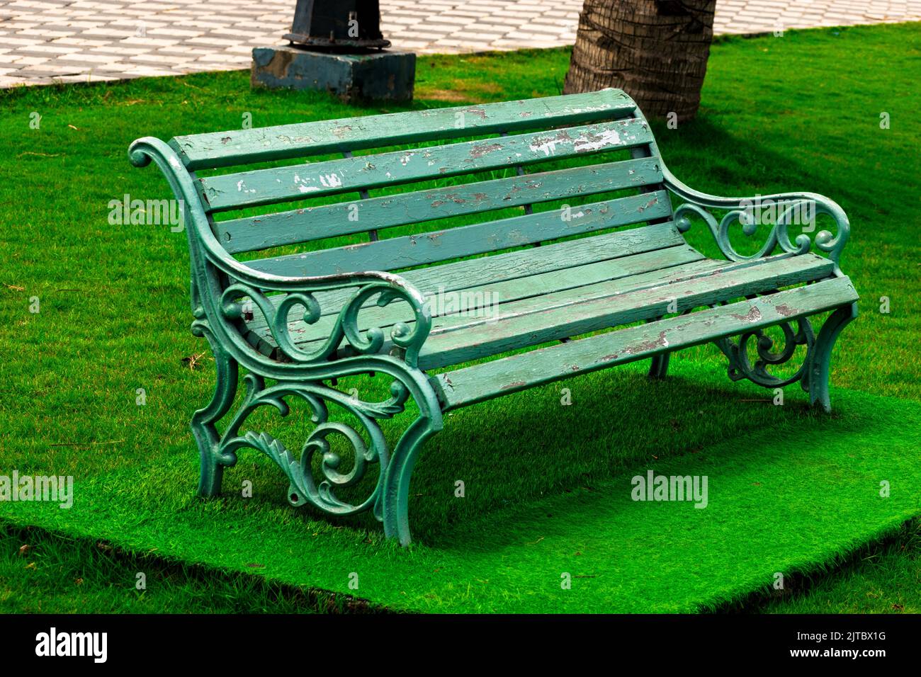 A green bench surrounded by green grass in a park. Selective focus on ...