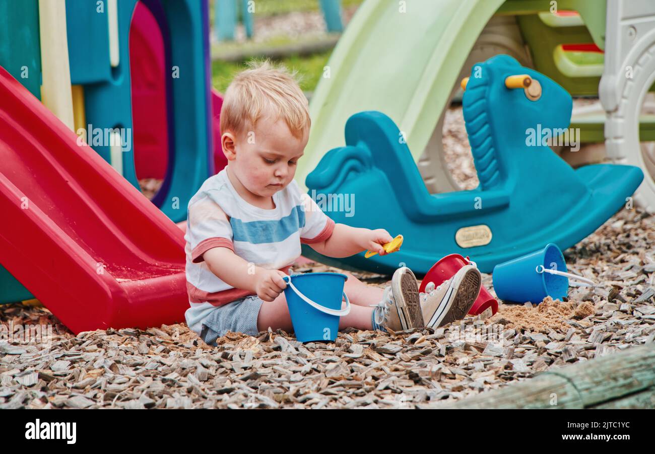 A closeup of a cute child with a bucket and spade toy sitting on the ...