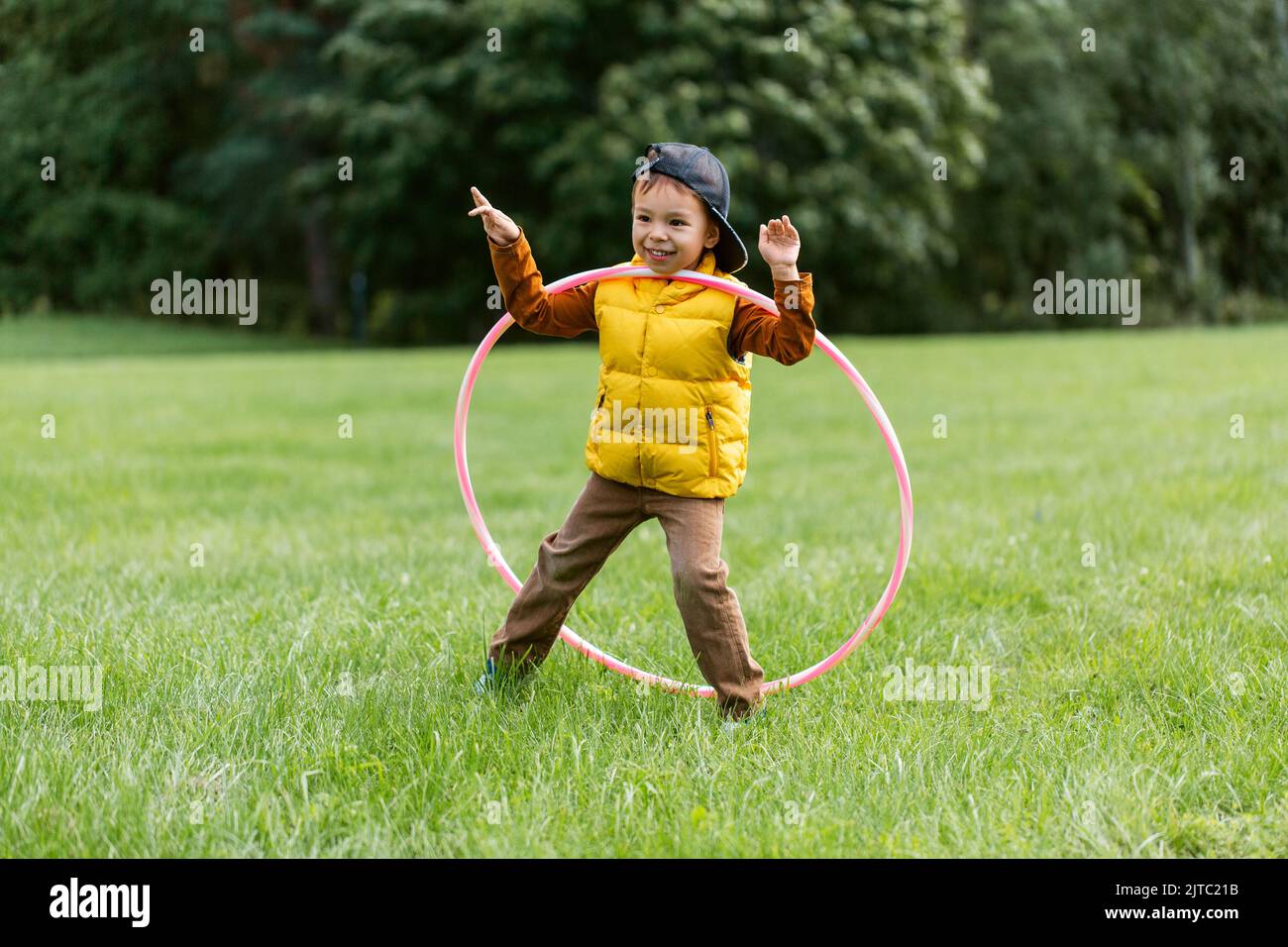 happy little boy playing with hula hoop at park Stock Photo - Alamy
