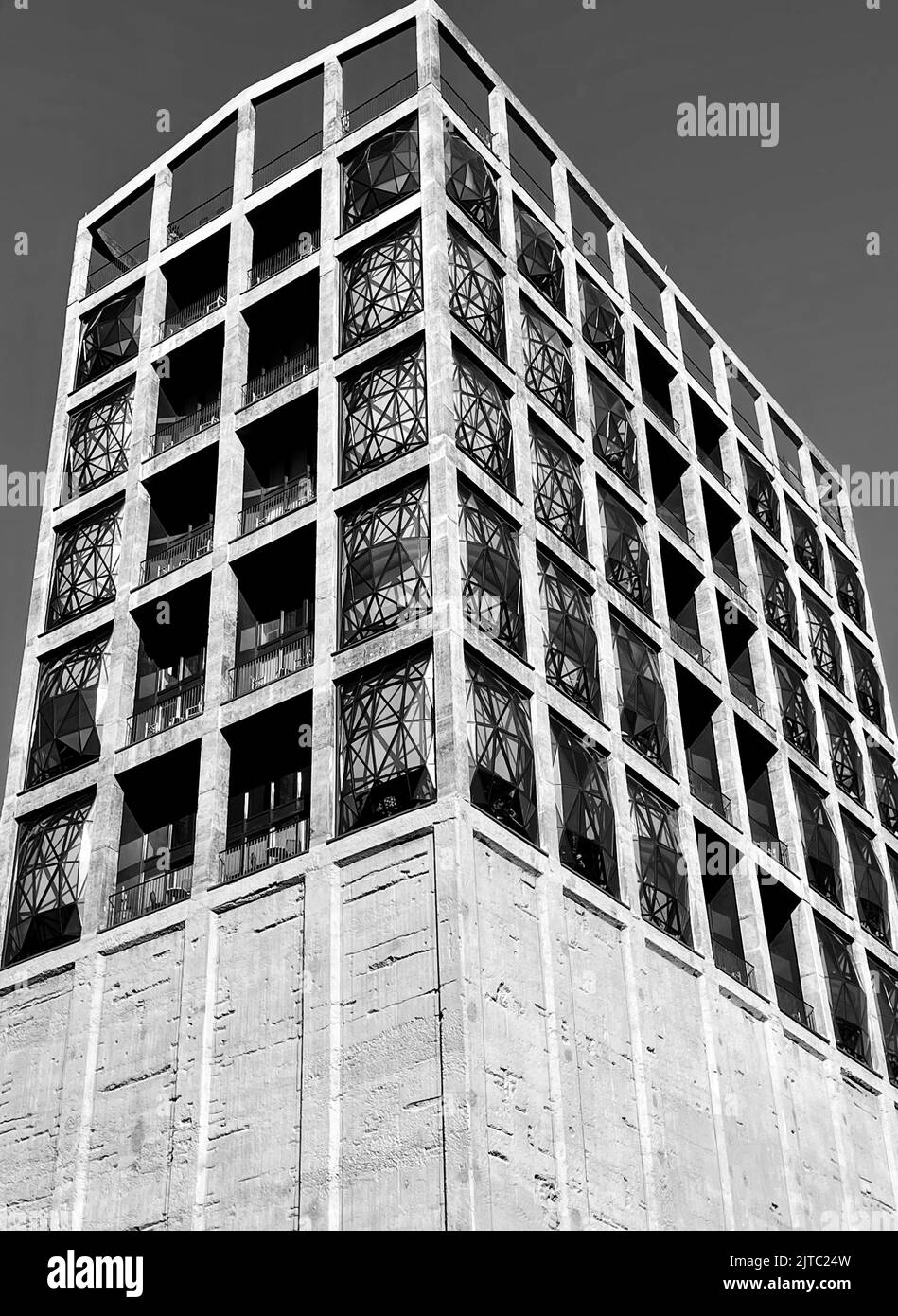 A vertical grayscale of a modern building with unique window designs ...