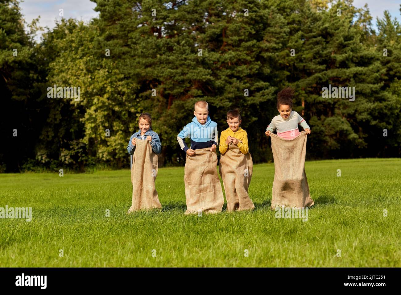 happy children playing bag jumping game at park Stock Photo - Alamy