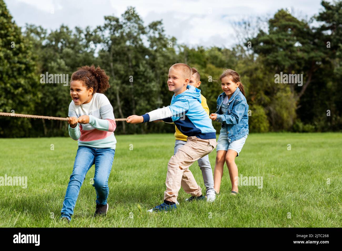 happy children playing tug-of-war game at park Stock Photo - Alamy