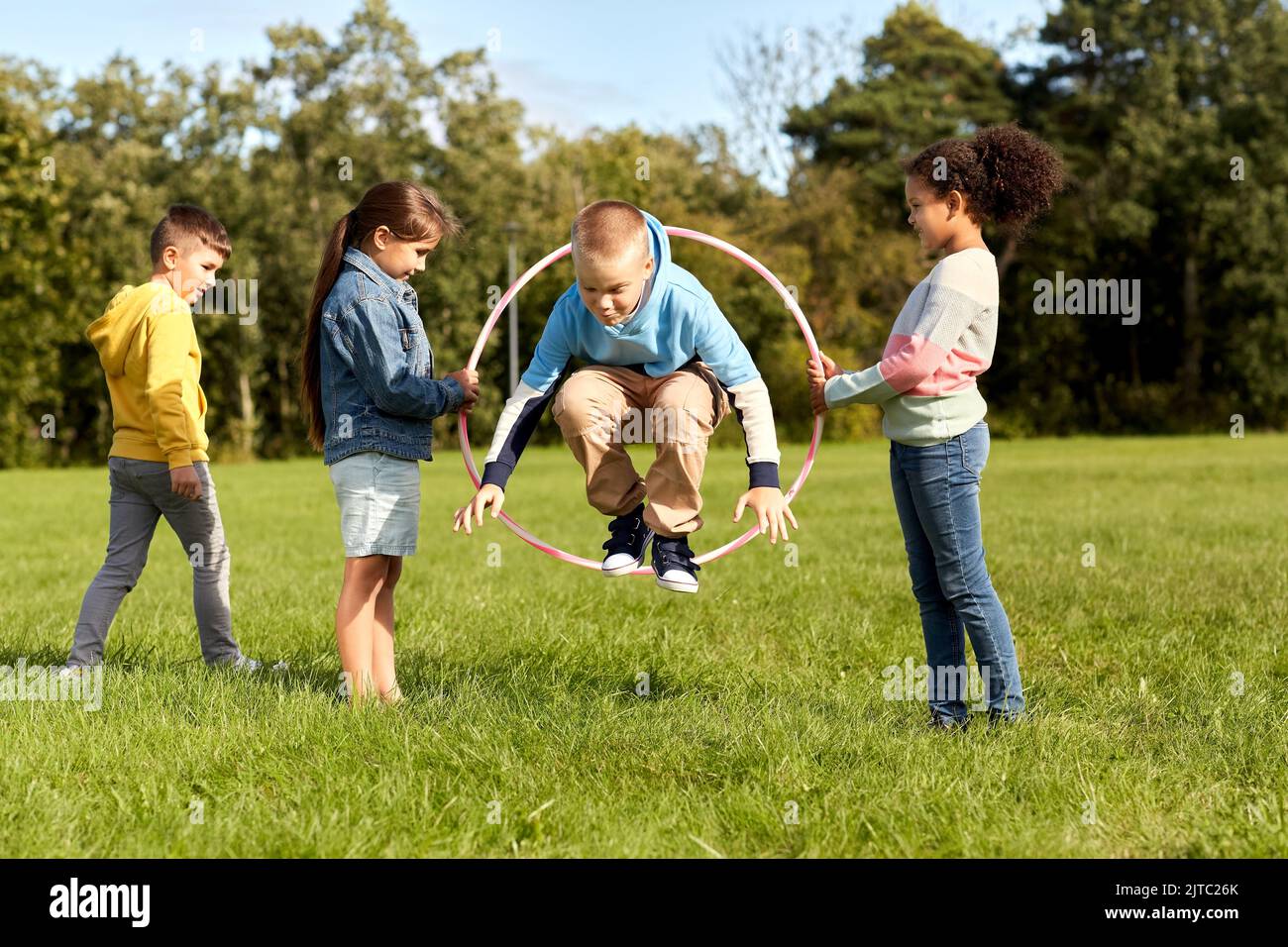 happy children jumping through hula hoop at park Stock Photo - Alamy