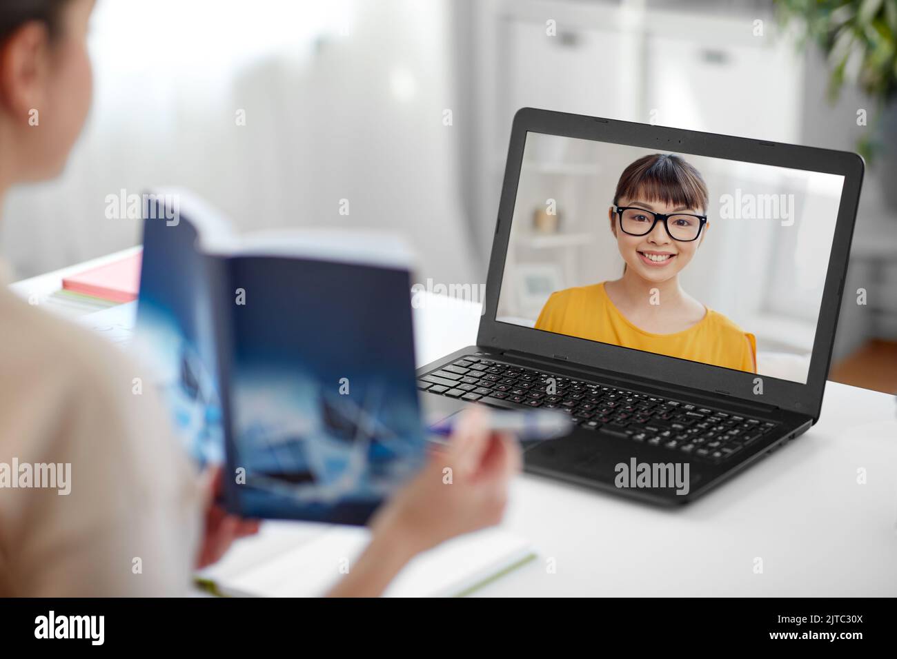 teacher with book and student on laptop screen Stock Photo - Alamy