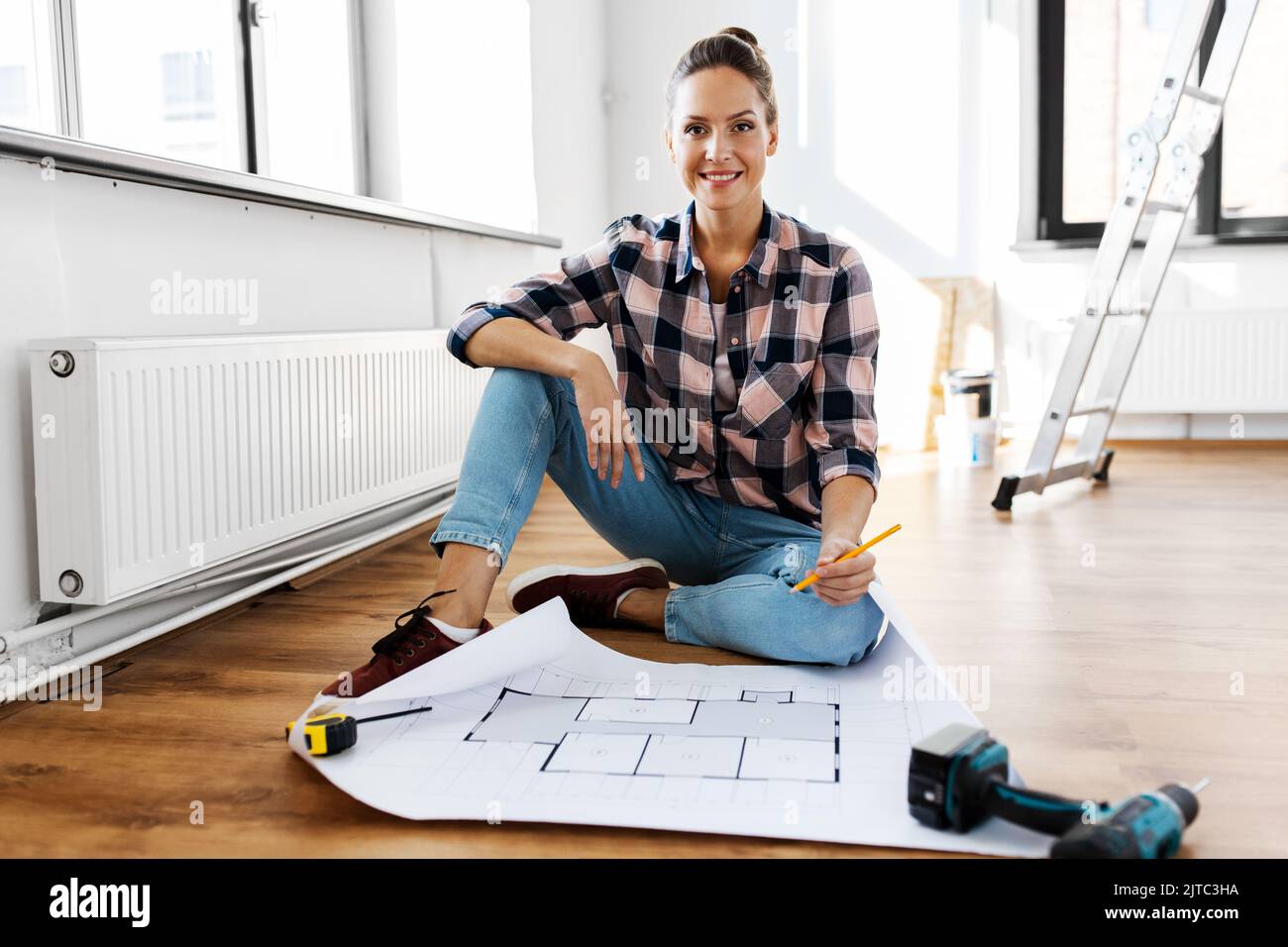 woman with blueprint sitting on floor at home Stock Photo - Alamy