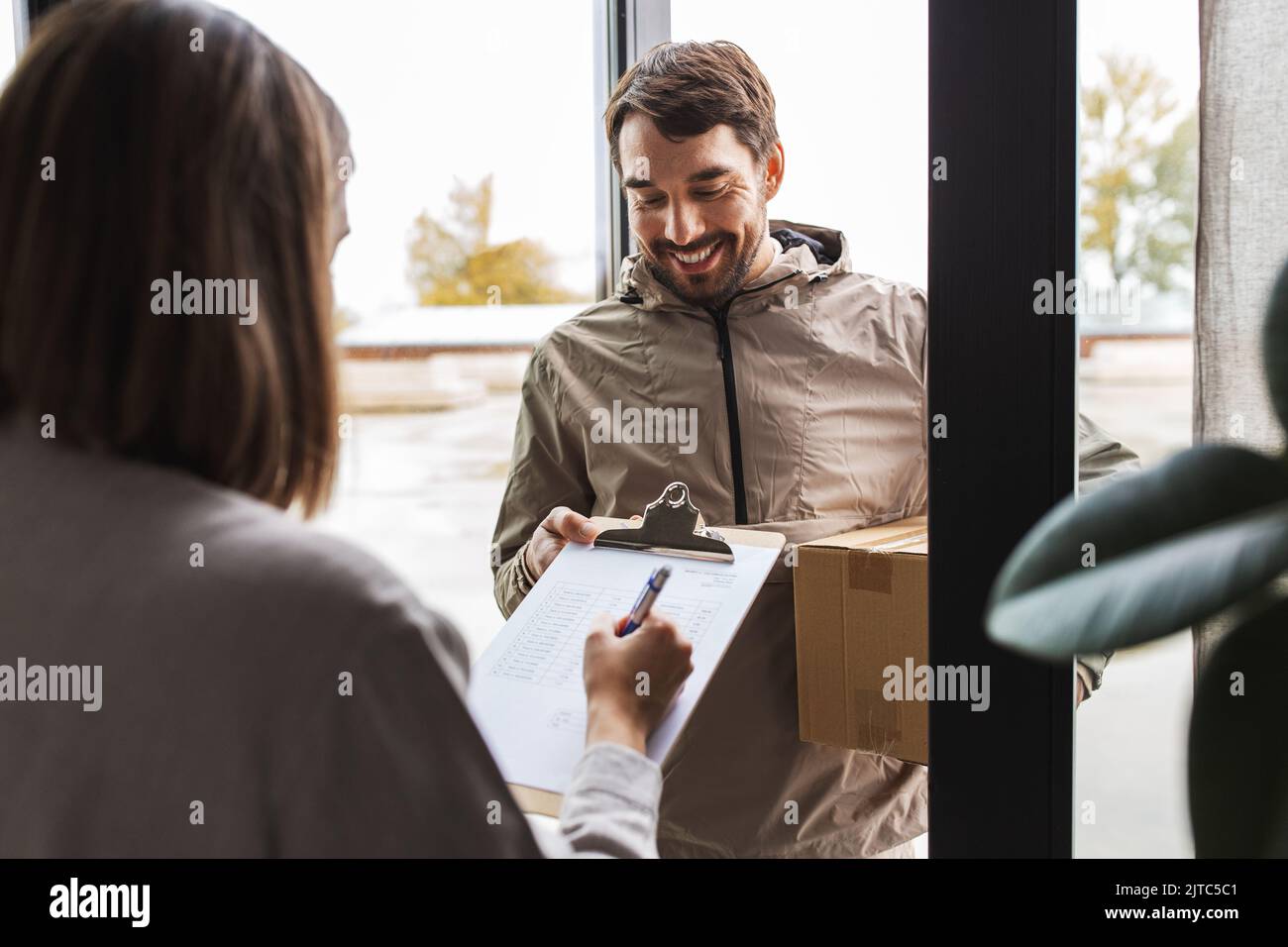 delivery man with parcel box and customer at home Stock Photo - Alamy