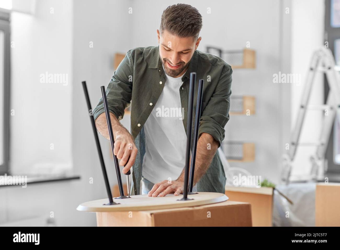 happy man assembling coffee table at new home Stock Photo - Alamy