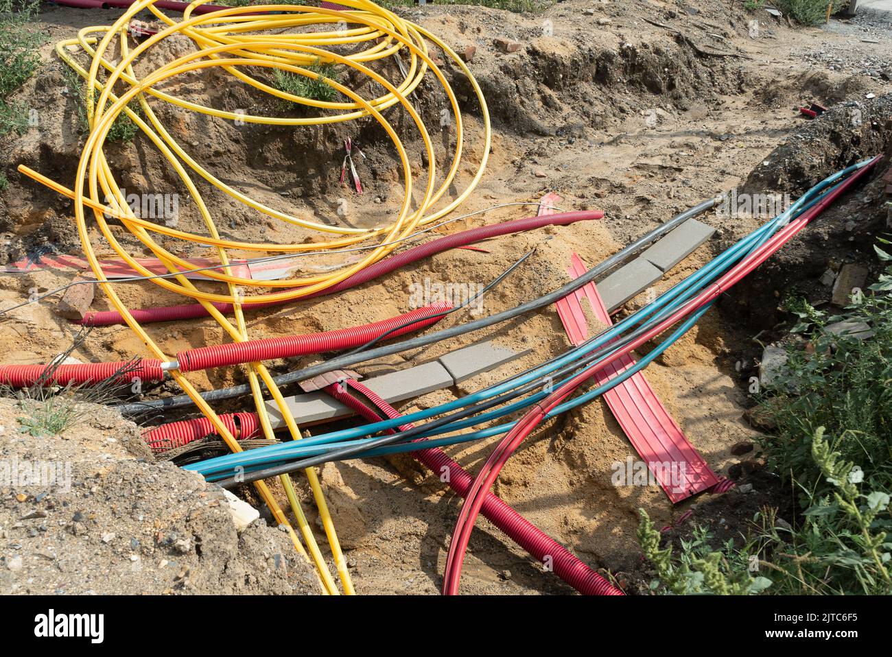 Network cables in red corrugated pipe are buried underground on the ...