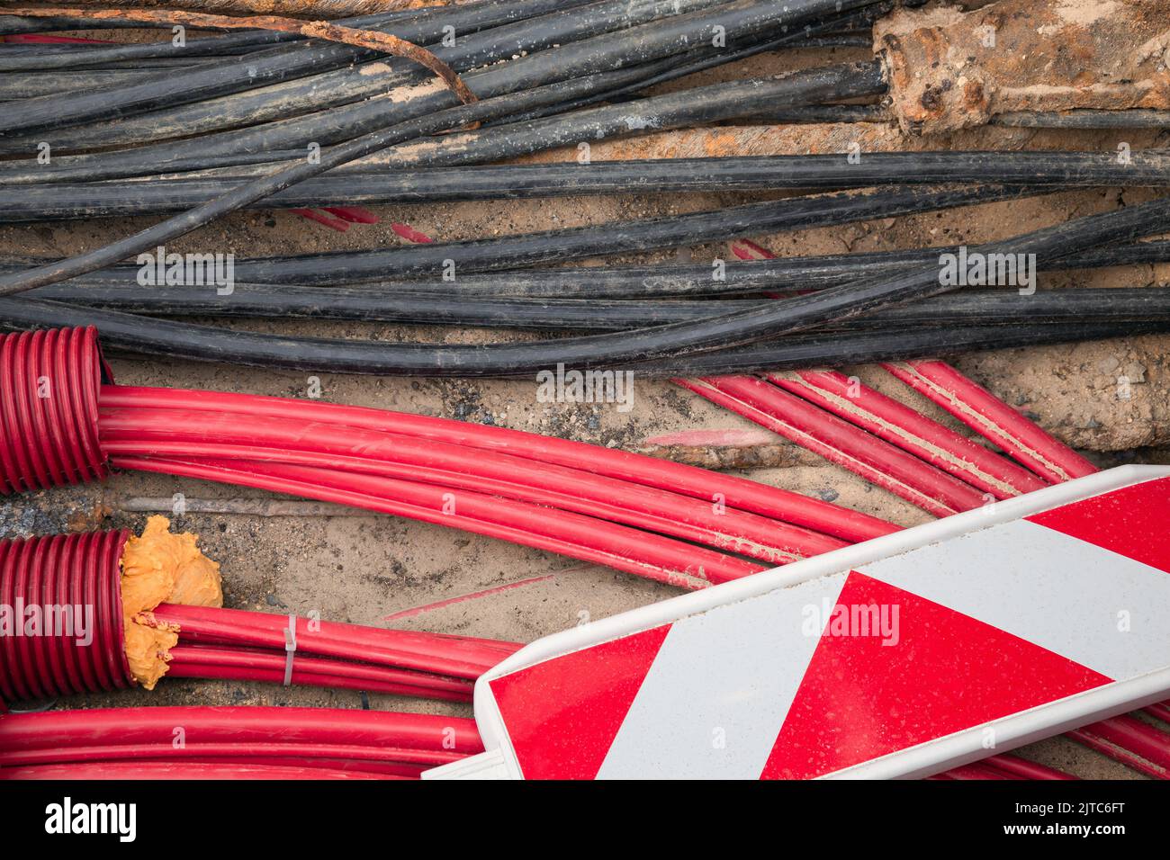 Network cables in red corrugated pipe are buried underground on the ...