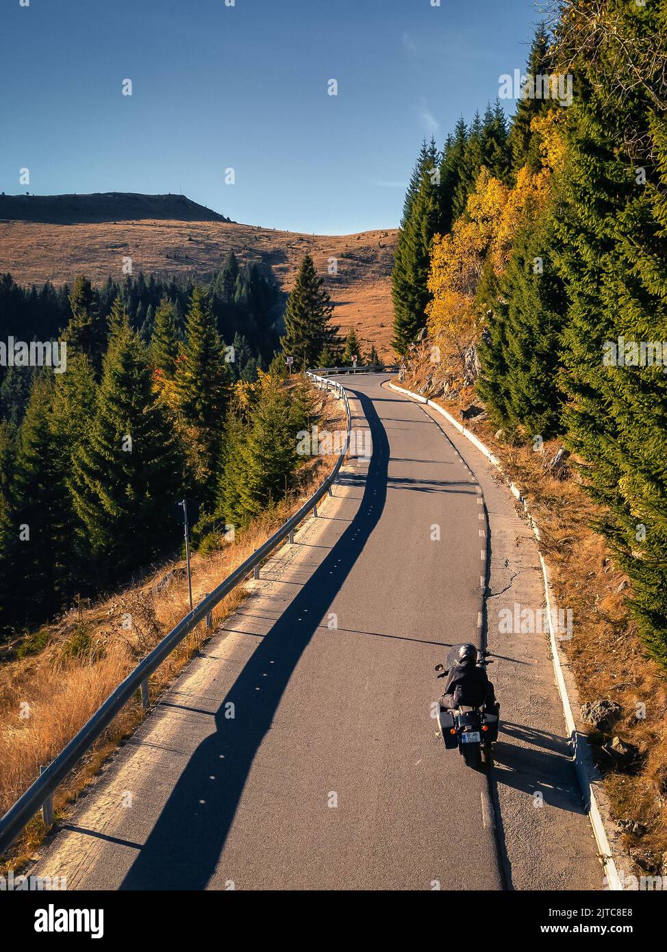 A vertical shot of Transbucegi road, where a motorcycle driver is ...