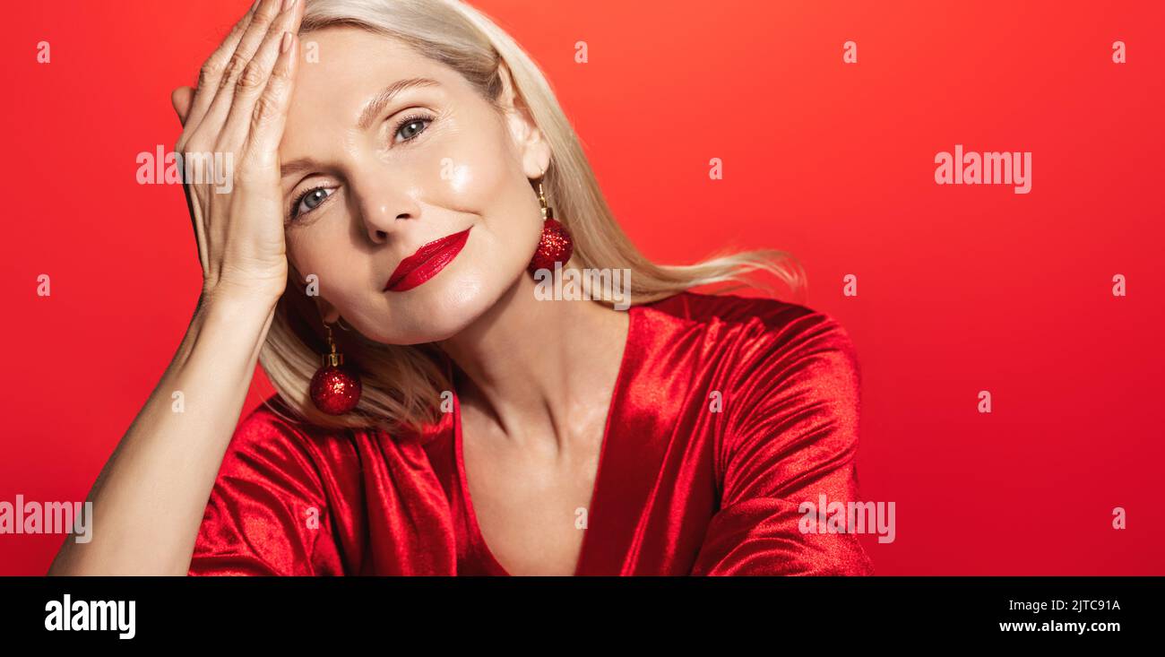 Smiling 50s elder woman, touches her flawless skin, nourished and ...