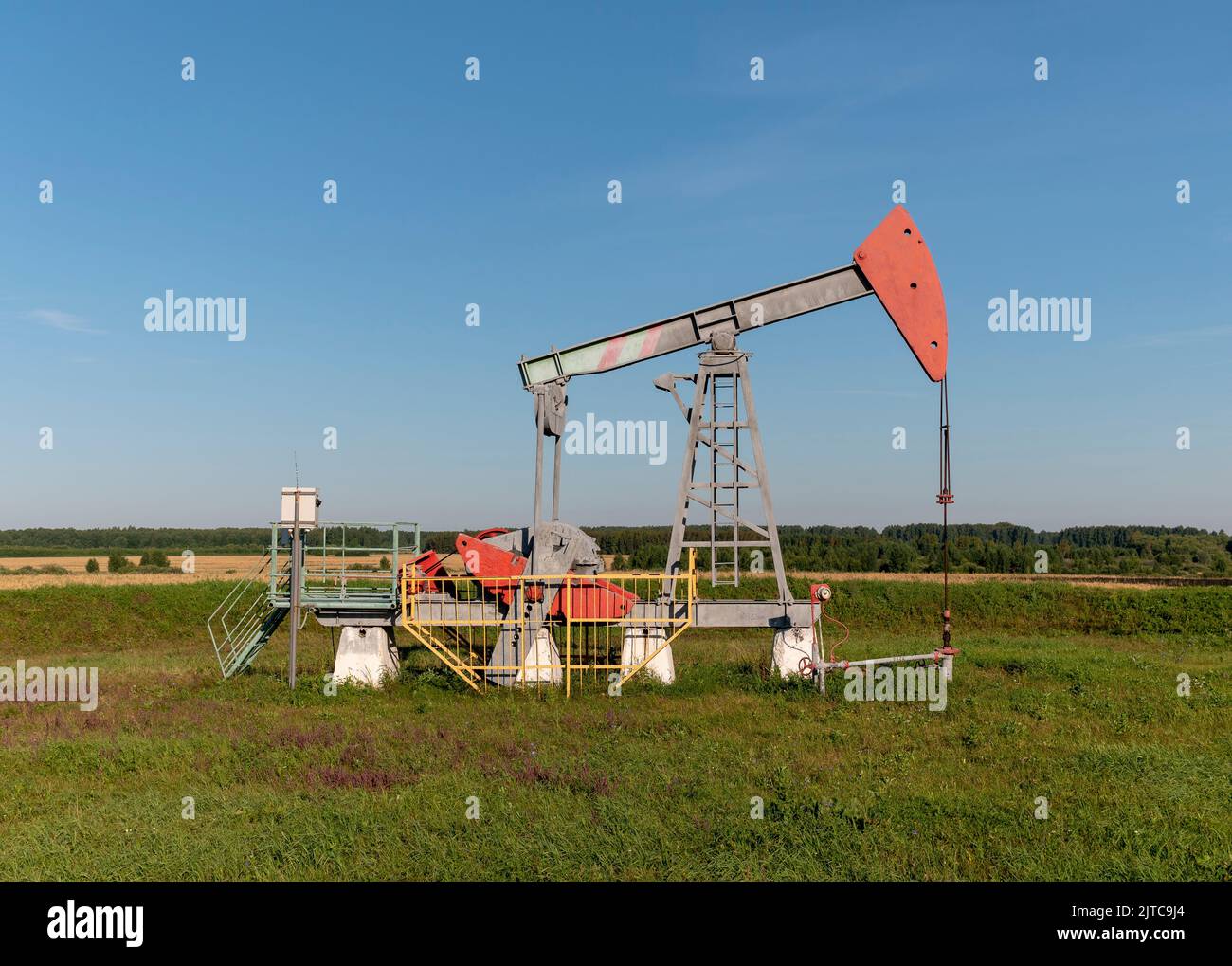 Operating oil and gas well in oil field, profiled against the blue sky ...