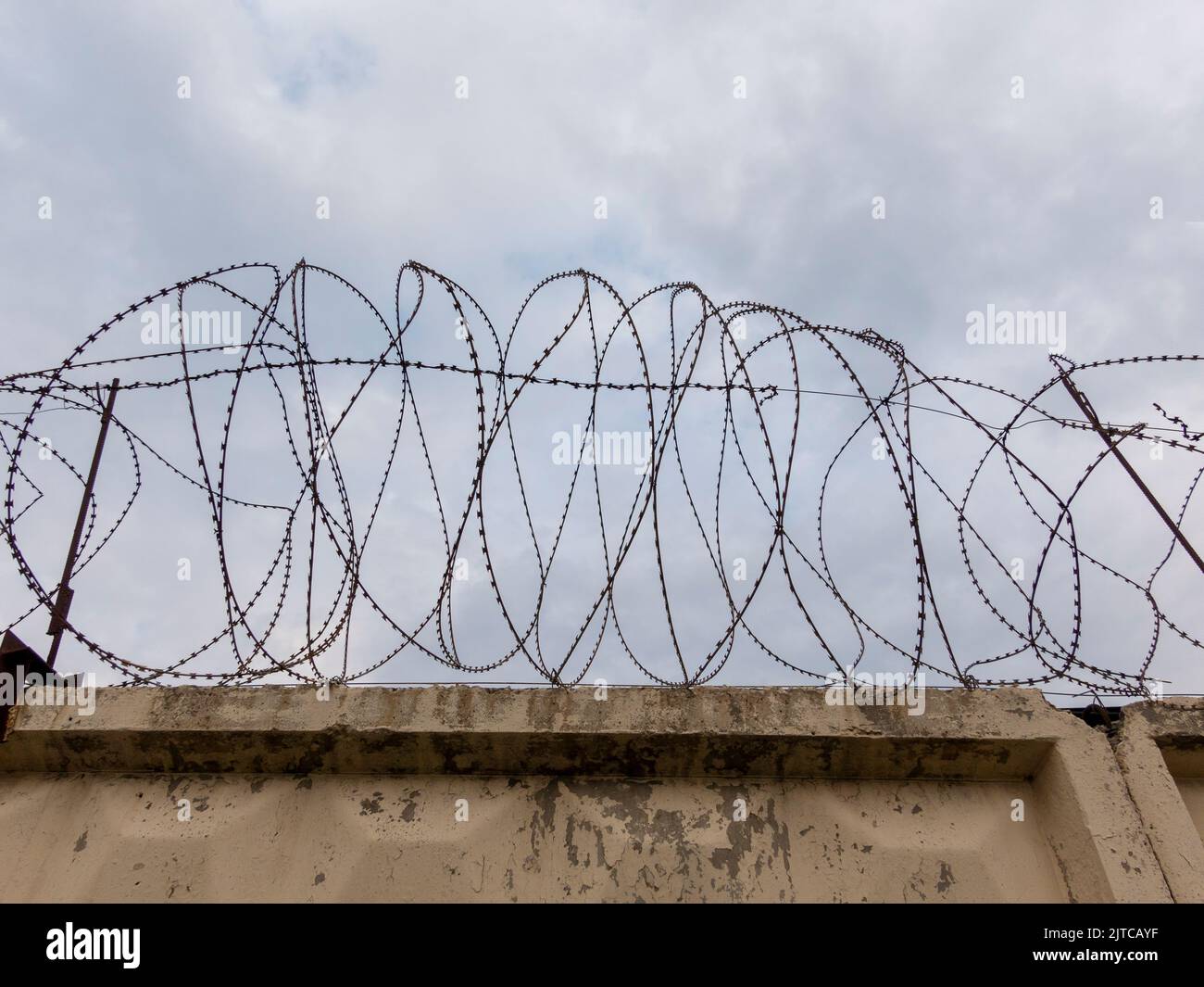 Coiled barbed wire fencing against a blue sky background Stock Photo ...
