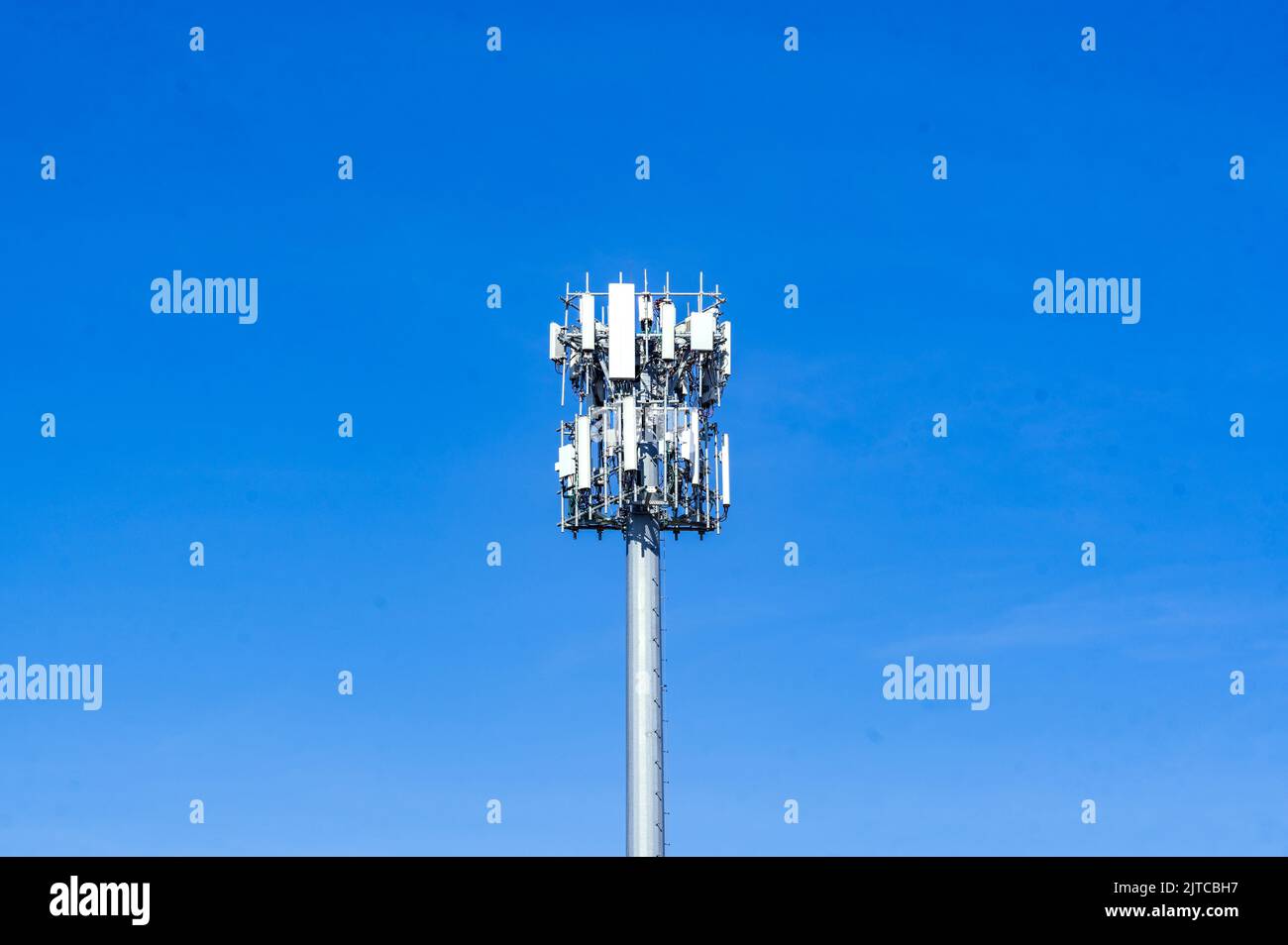 Cell tower against blue sky in middle Stock Photo - Alamy