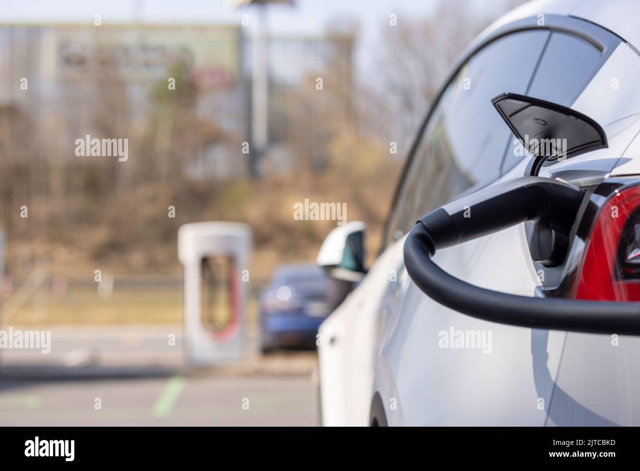 Electric car charger plugged in a vehicle socket at charging station ...