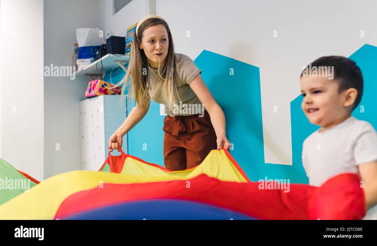 Happy toddler and his teacher engaged in an active sensory play with ...