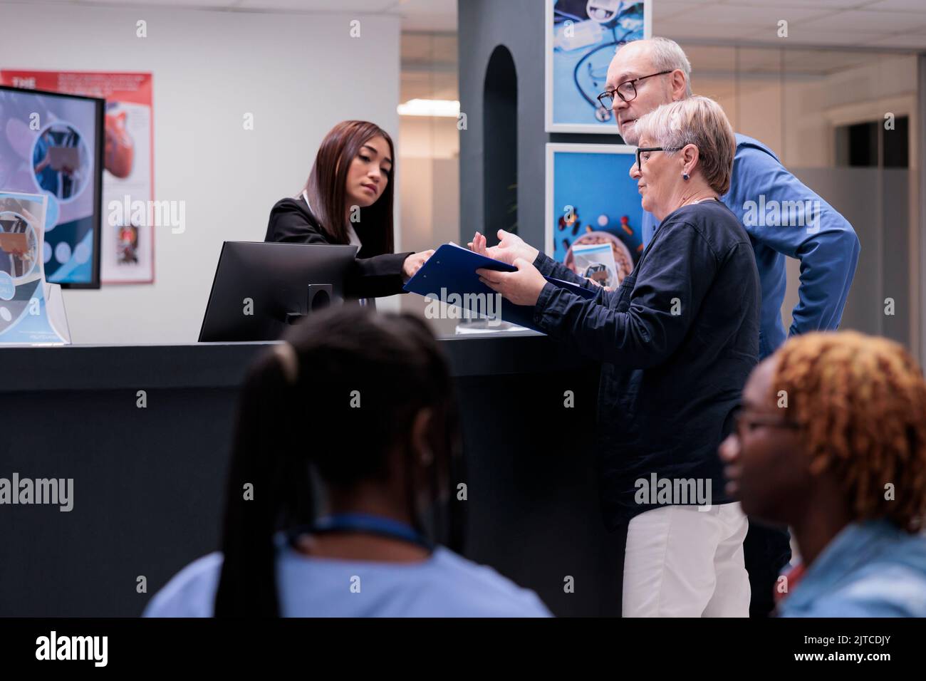 Old patients writing medical report papers with receptionist before ...