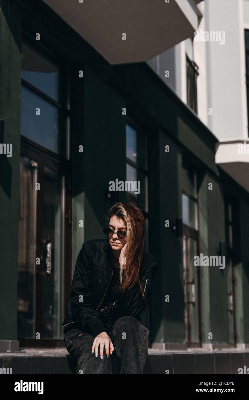 a young girl sits near a beautiful green building Stock Photo - Alamy