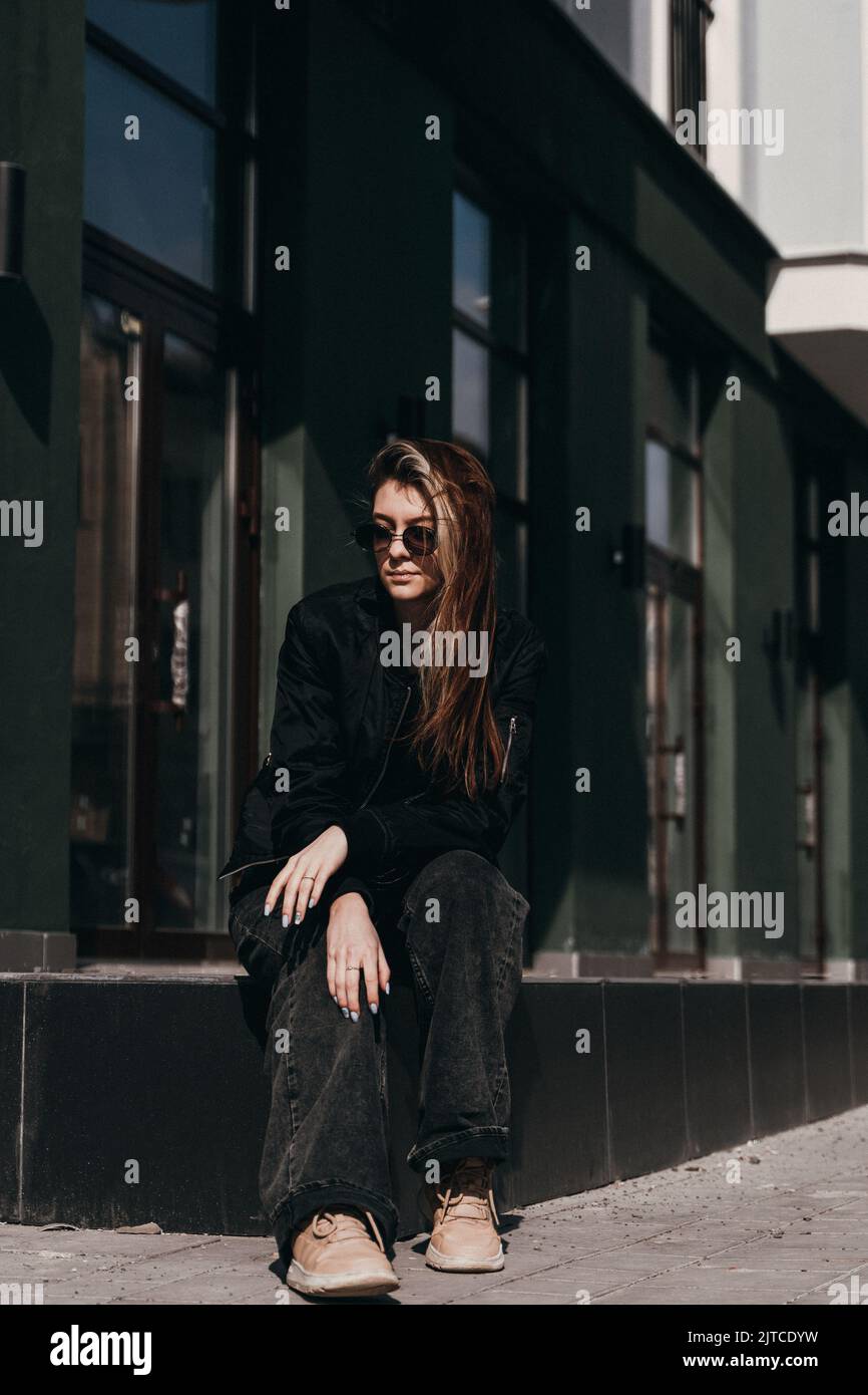 a young girl sits near a beautiful green building Stock Photo - Alamy