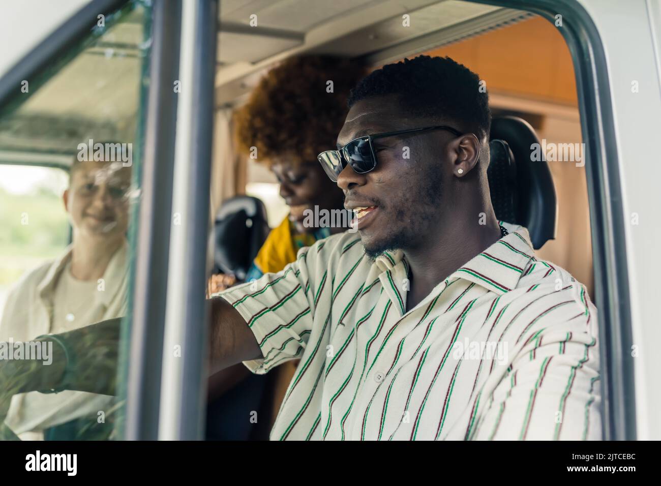 Afro-American man with his friends driving a van, medium closeup ...