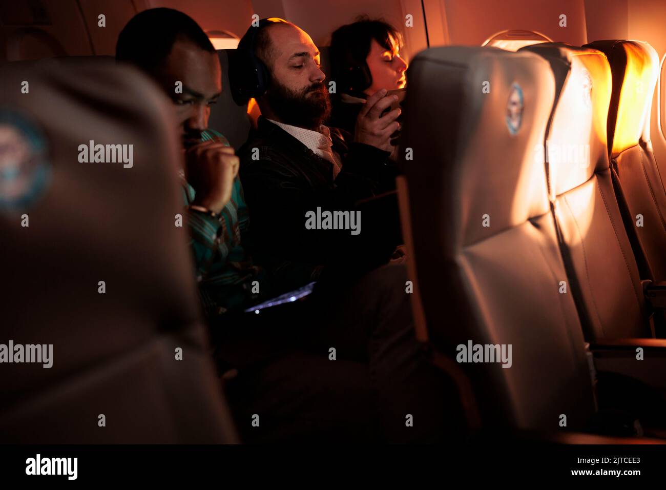 Diverse passengers flying in economy class with airplane jet, using ...