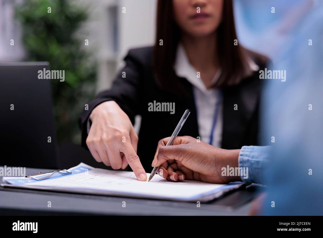 Person filling in report files at reception desk, signing registration ...