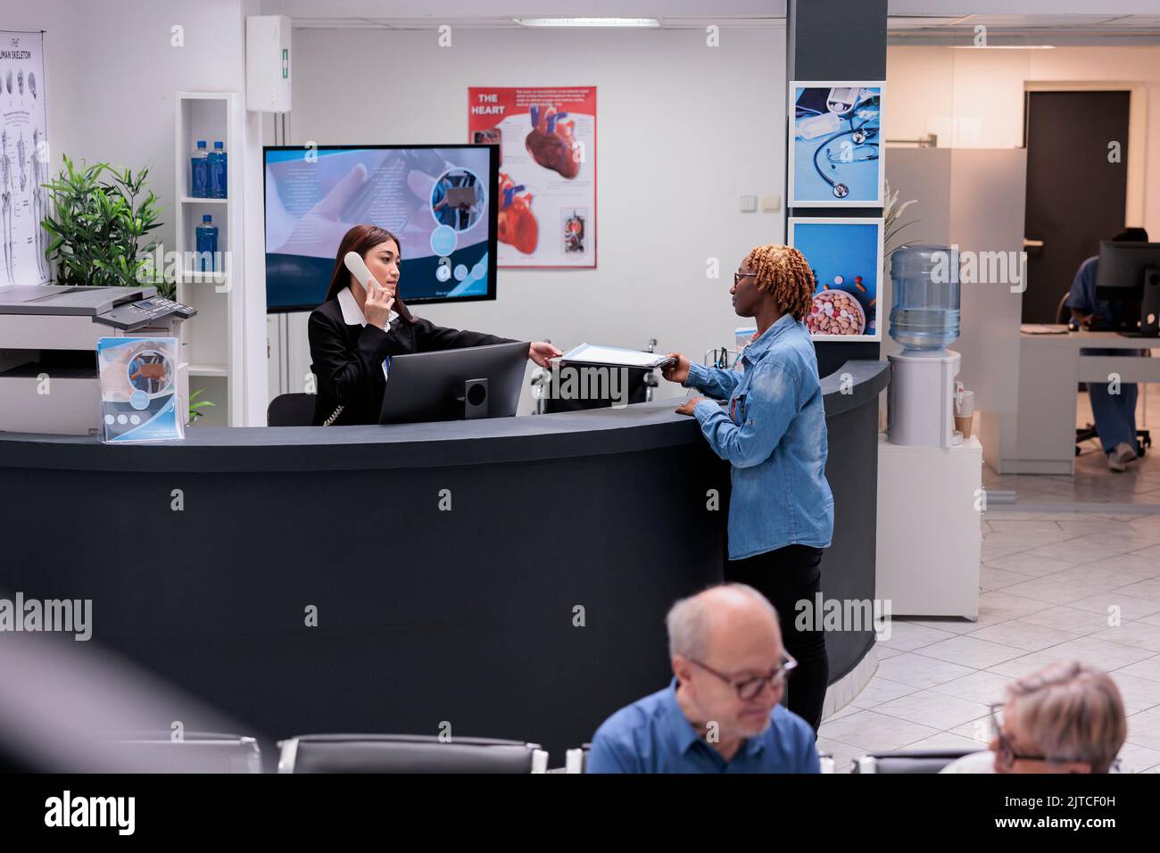 Receptionist using landline phone at reception desk, giving report ...