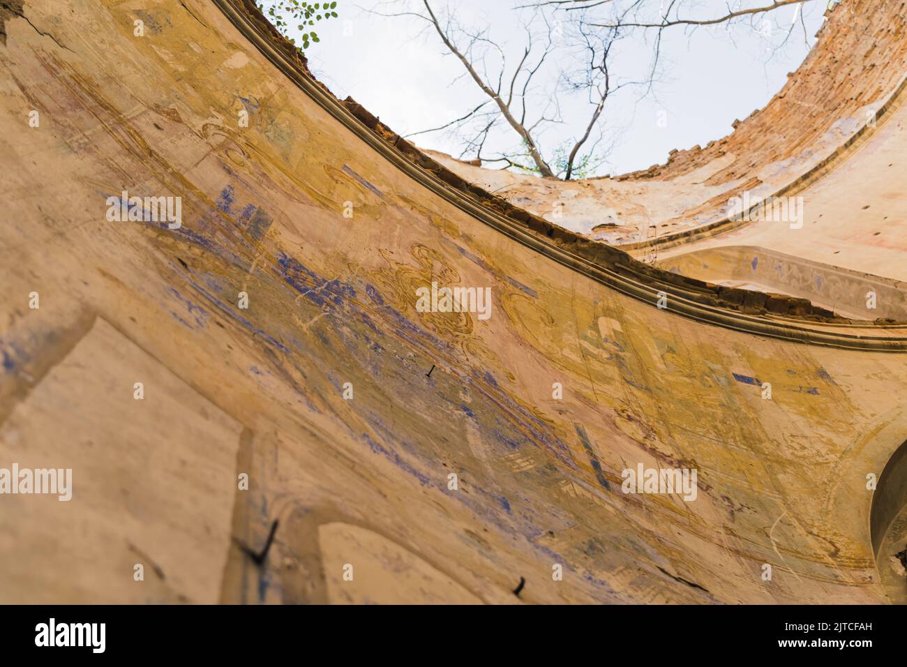 Damaged church wall with faded frescos and tower with no roof. Sky and ...