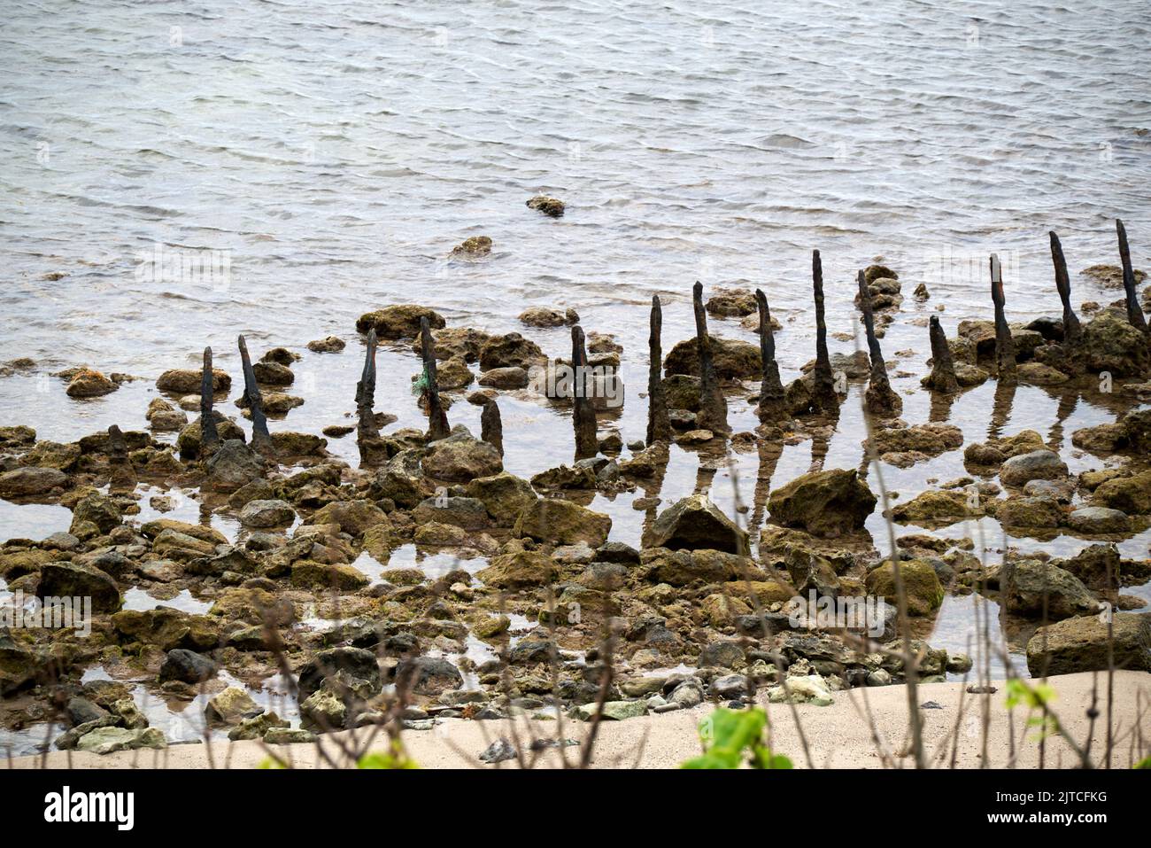 A closeup of rocks and metal spikes on the sandy shore Stock Photo - Alamy