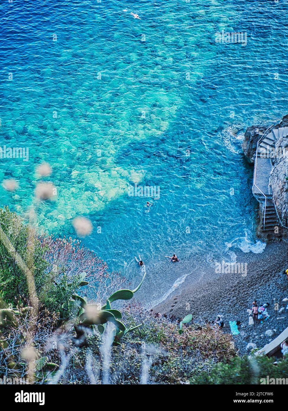 A drone view of a blue ocean with people swimming and sunbathing on the ...
