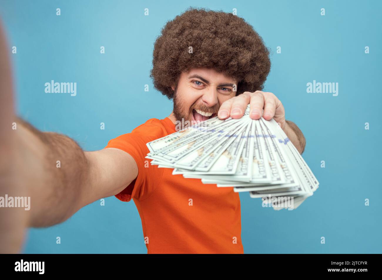 Portrait of crazy rich man with Afro hairstyle wearing orange T-shirt ...