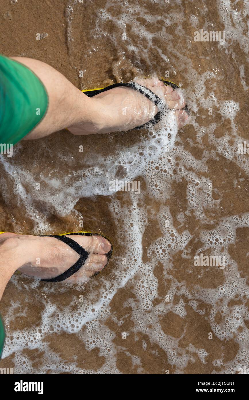 Top to bottom view of feet on the beach sand. Barra beach lighthouse ...
