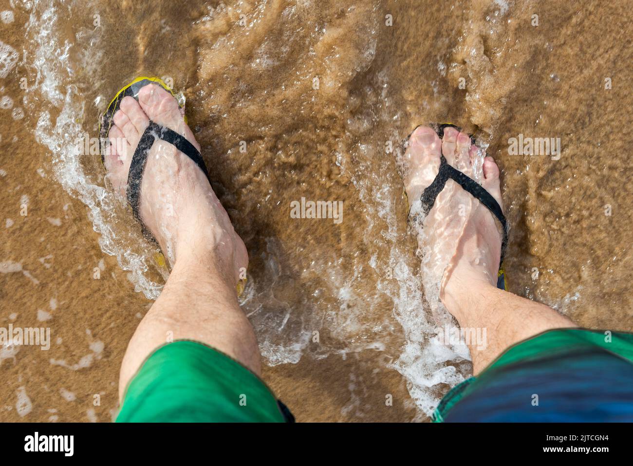 Top to bottom view of feet on the beach sand. Barra beach lighthouse ...