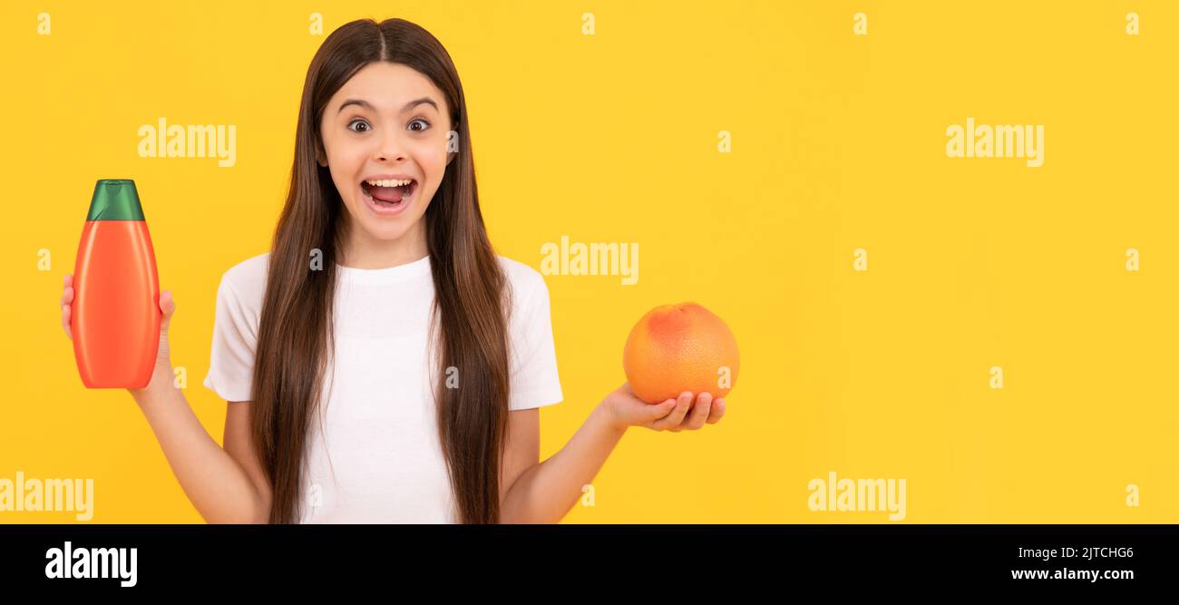 amazed child hold shampoo bottle and grapefruit on yellow background ...