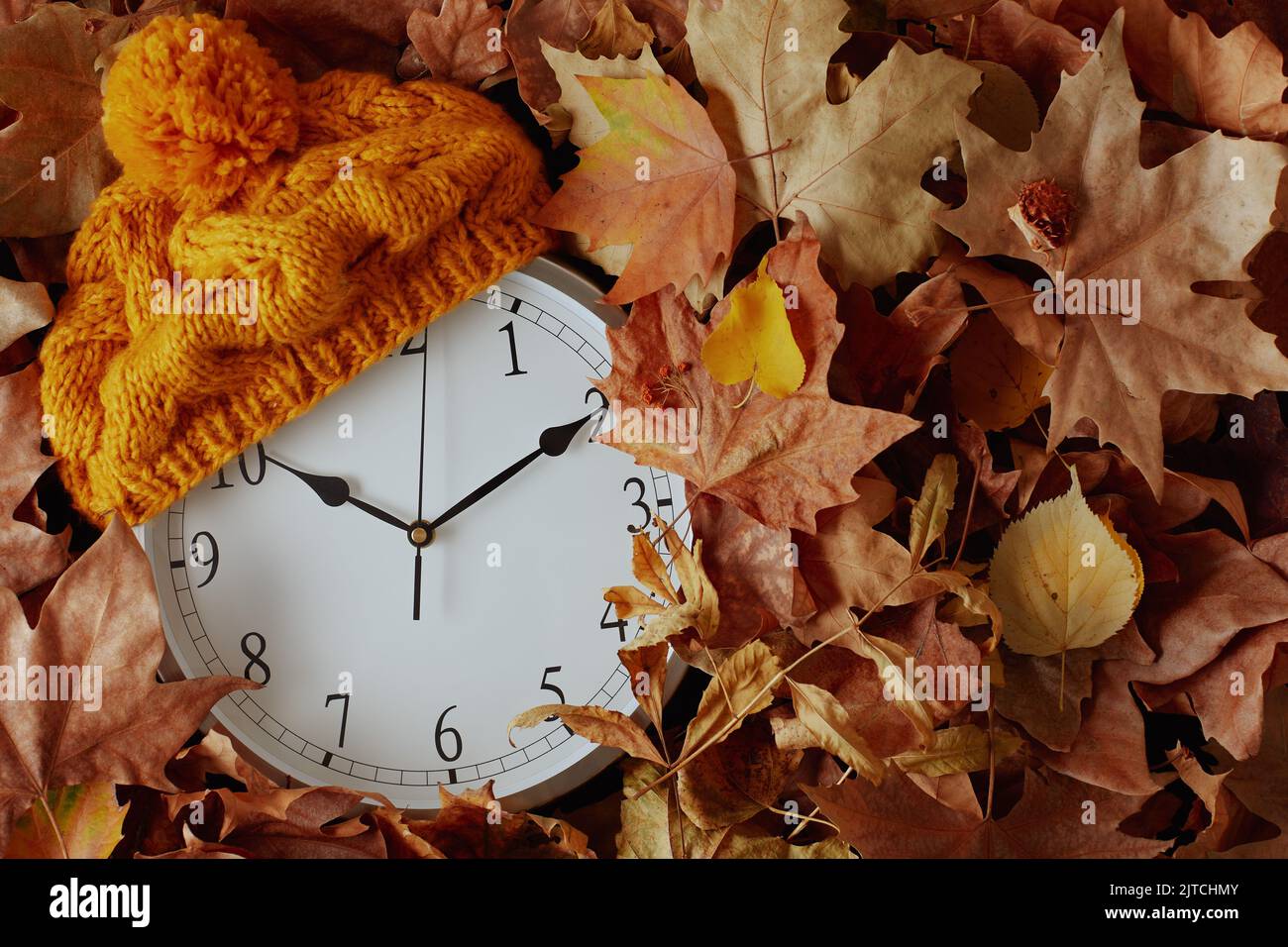 autumn background with clock, hat and leaves Stock Photo - Alamy