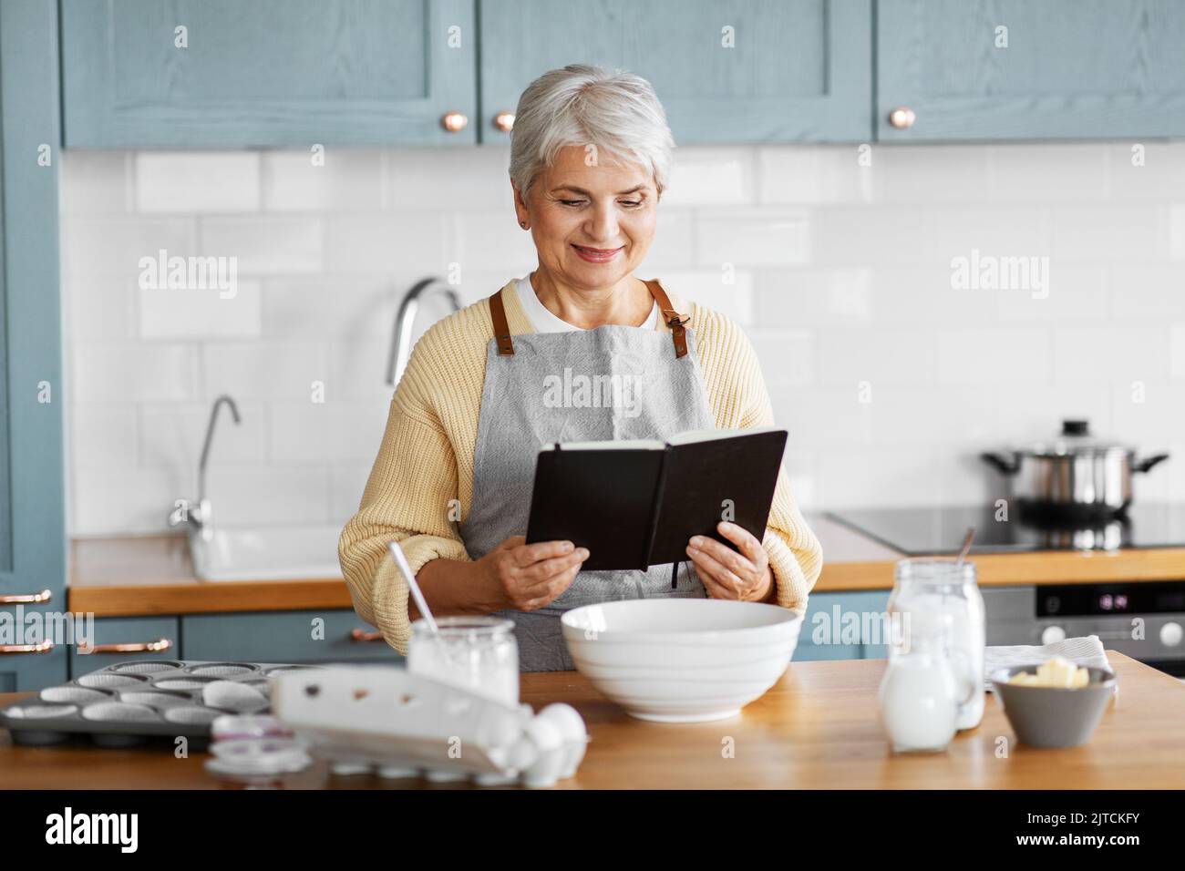 happy woman with cook book cooking food on kitchen Stock Photo - Alamy