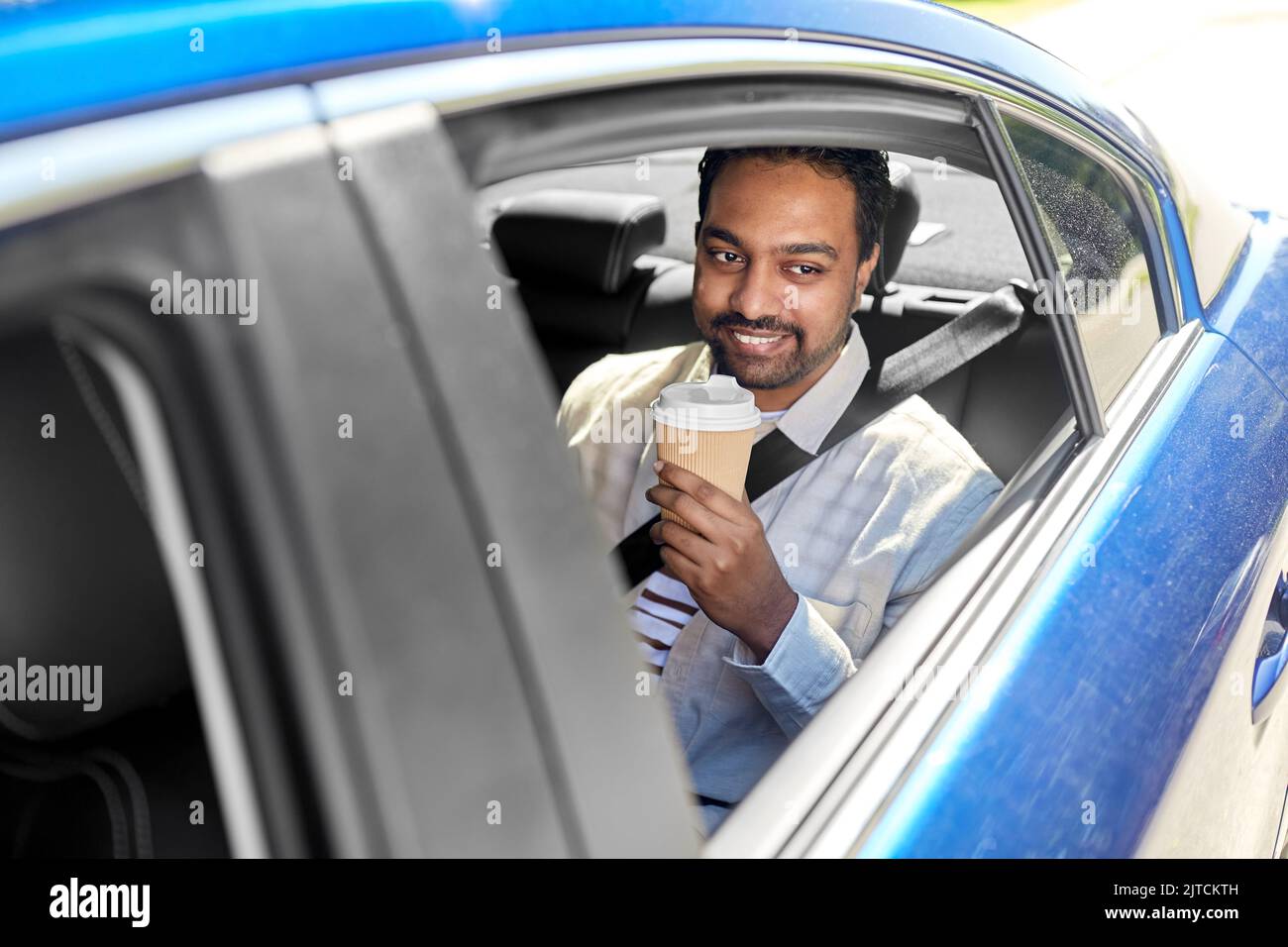 indian man with takeaway coffee on car back seat Stock Photo - Alamy