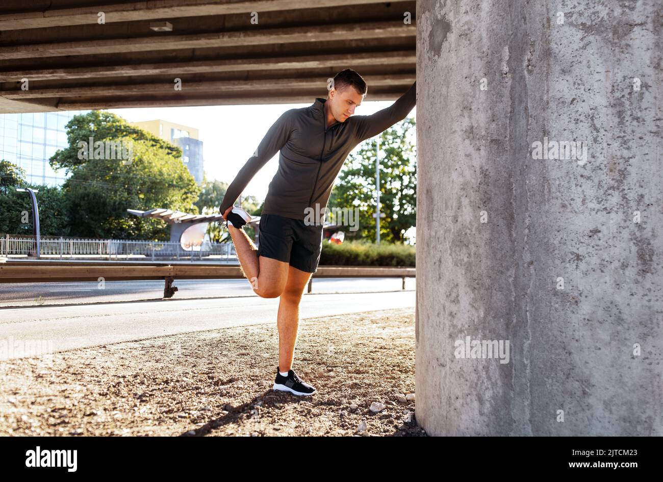 man stretching leg under bridge Stock Photo - Alamy