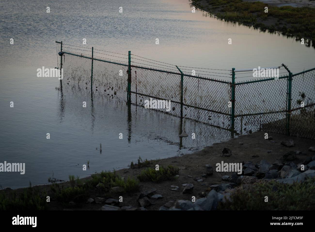 A beautiful view of a barbed wire fence in a water Stock Photo - Alamy