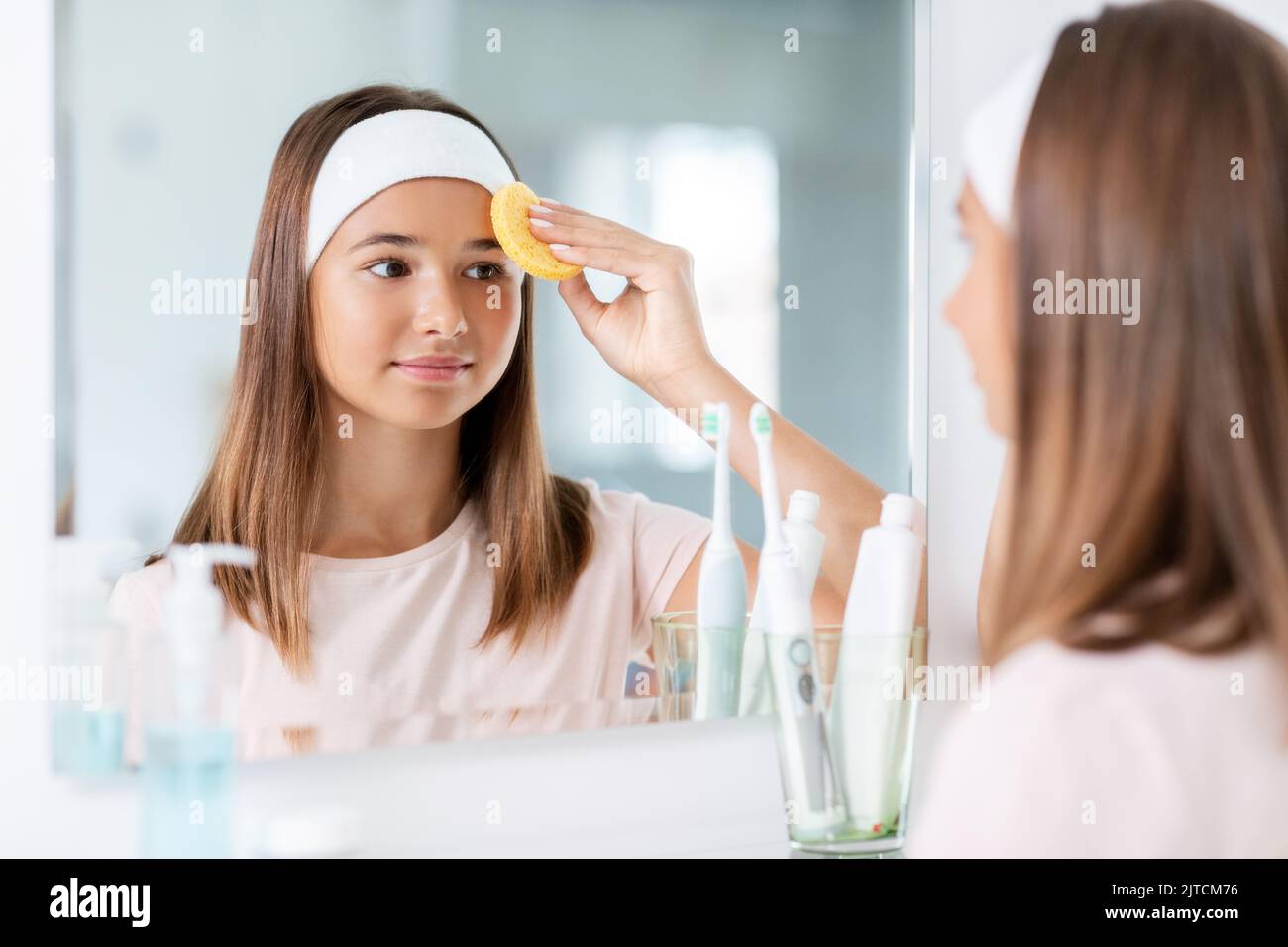 teenage girl cleaning face with sponge at bathroom Stock Photo - Alamy