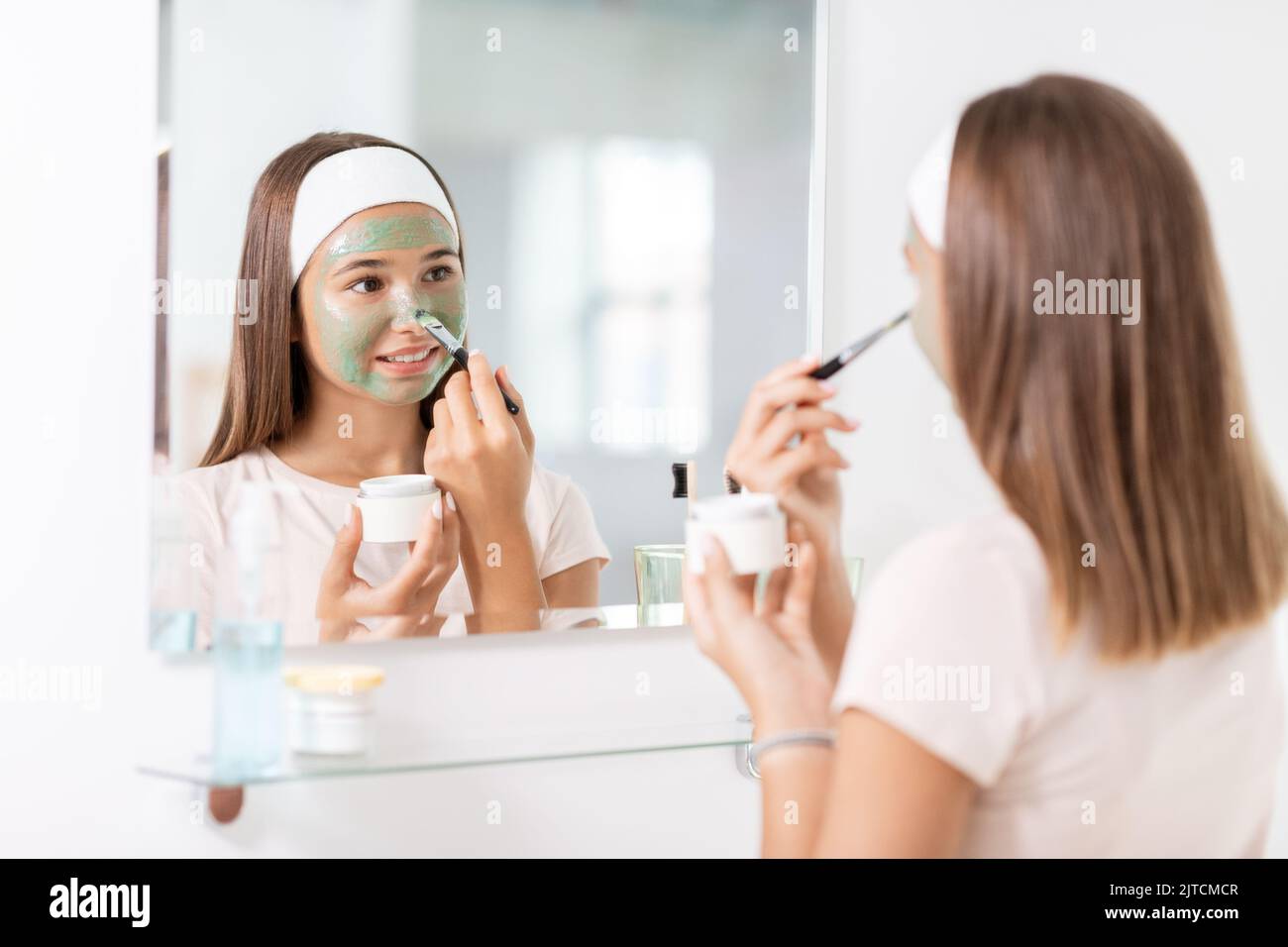 teenage girl applying mask to face at bathroom Stock Photo - Alamy