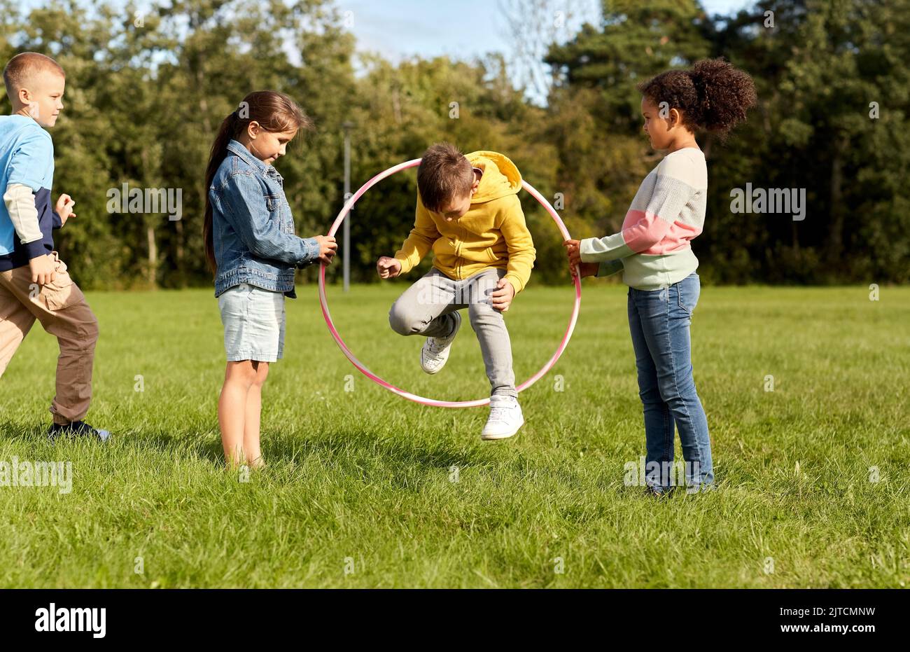 happy children jumping through hula hoop at park Stock Photo - Alamy