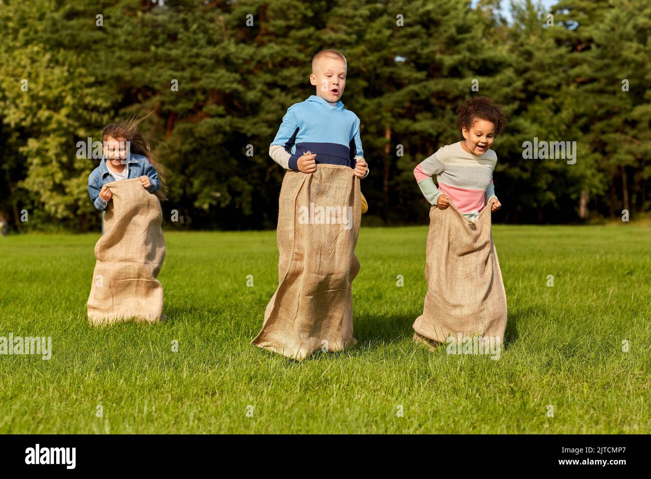 happy children playing bag jumping game at park Stock Photo - Alamy