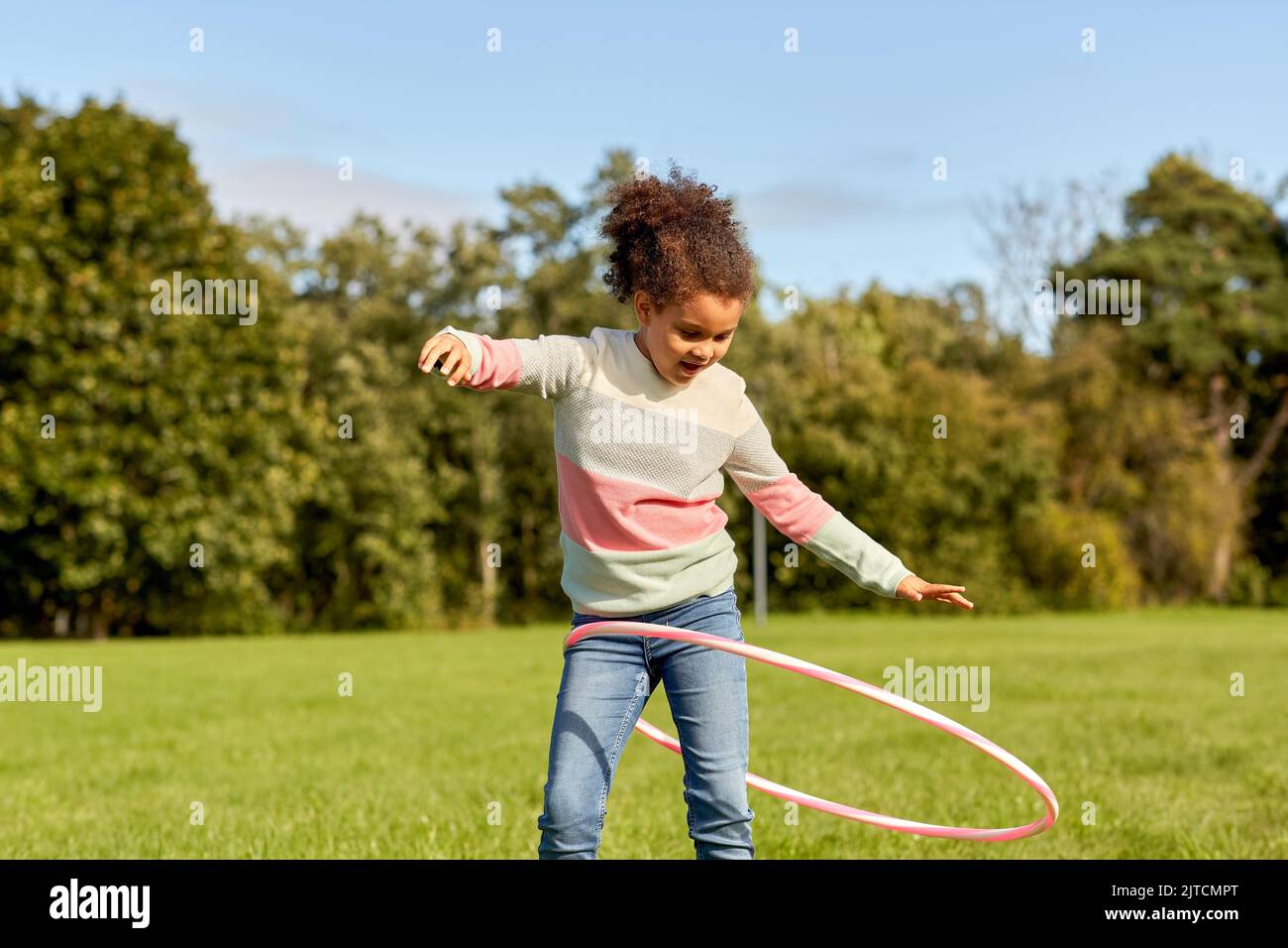 happy girl playing with hula hoop at park Stock Photo - Alamy