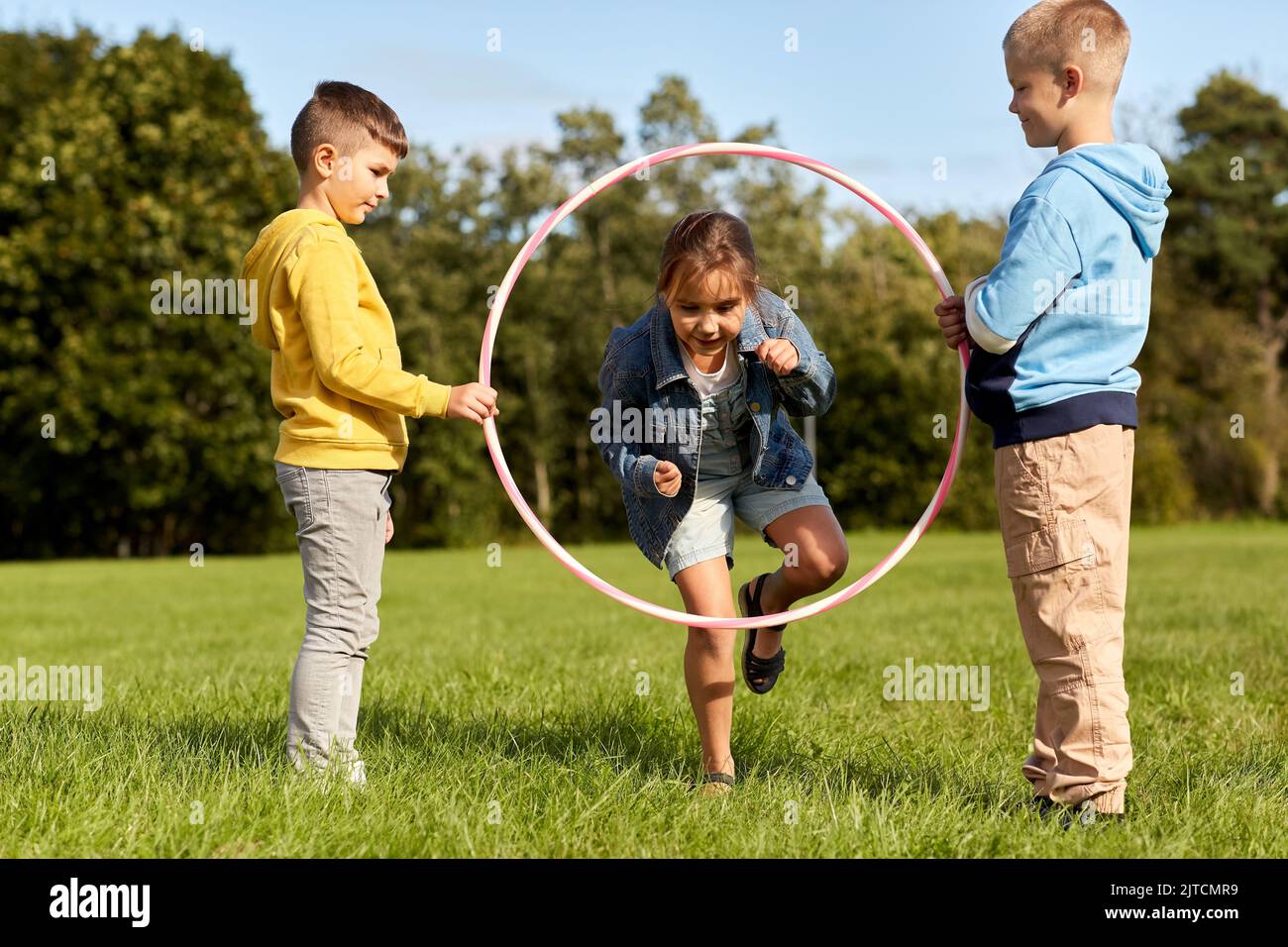 happy children playing game with hula hoop at park Stock Photo - Alamy