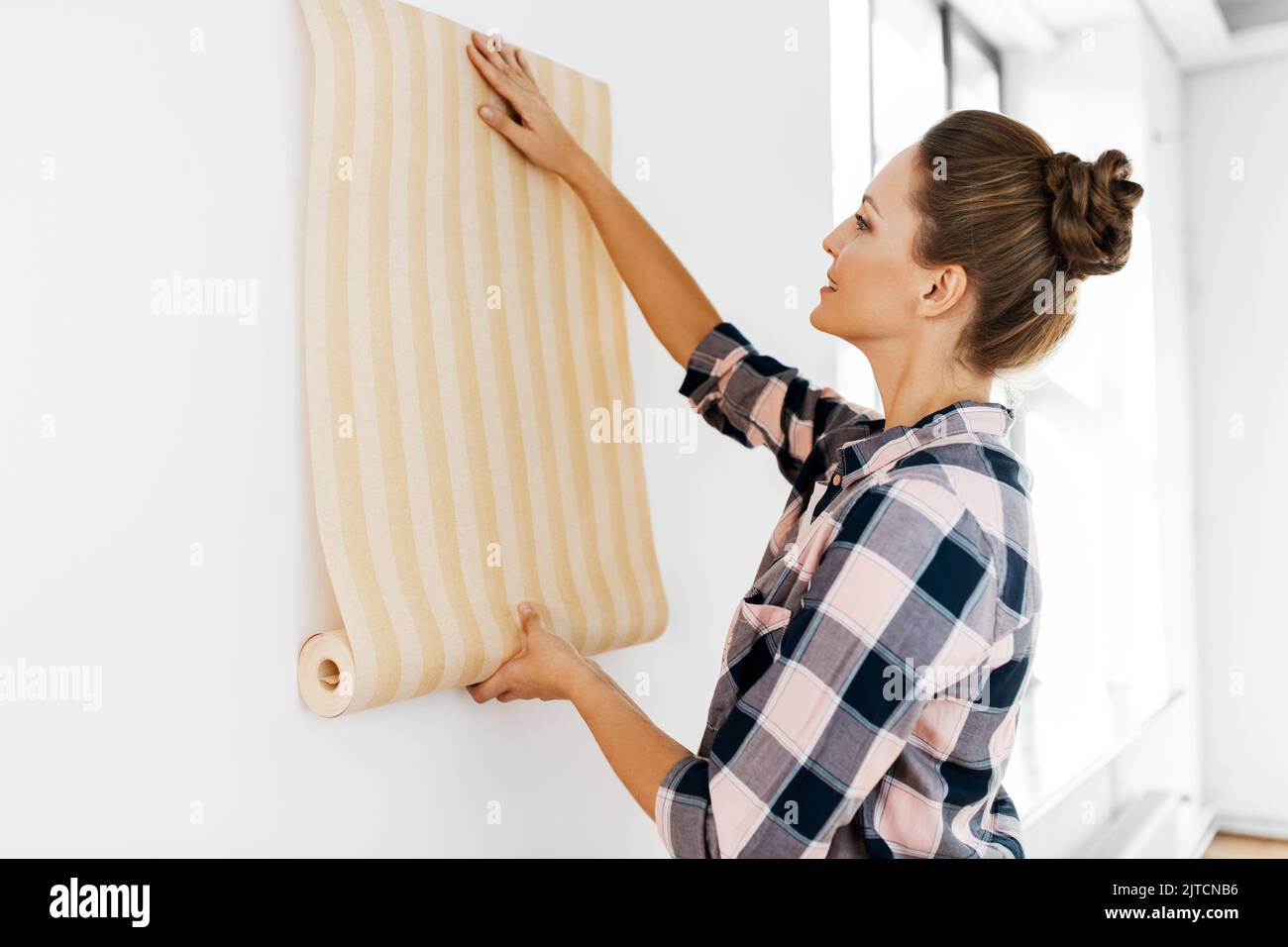 woman applying wallpaper to wall at home Stock Photo - Alamy